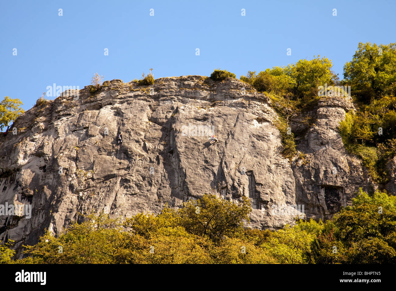 Rock climbers can barely be seen climbing the sheer rock face in the ...