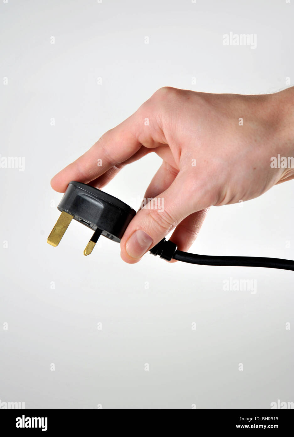 UK style 3 pin plug held in a hand as if to put into a 240V mains ...