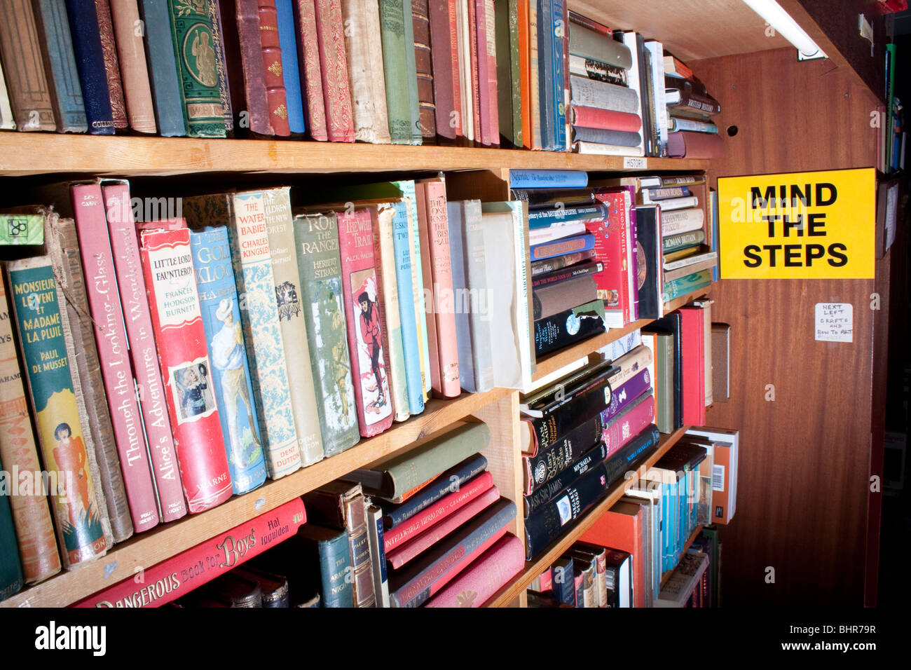Yellow Mind The Steps sign in a second hand book shop Stock Photo - Alamy