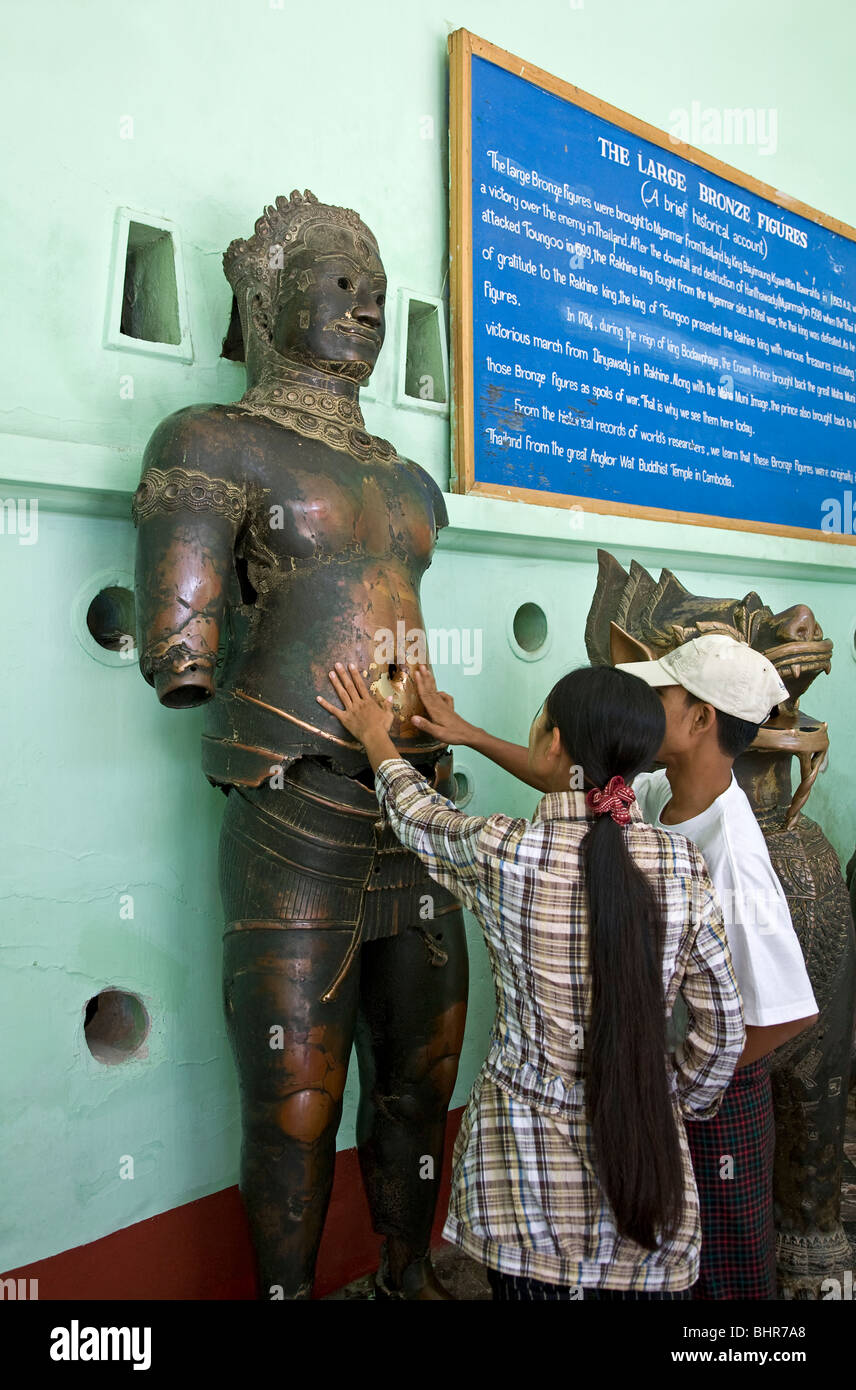 Burmese couple rubbing a bronze sculpture (cure ritual). Mahamuni Paya ...