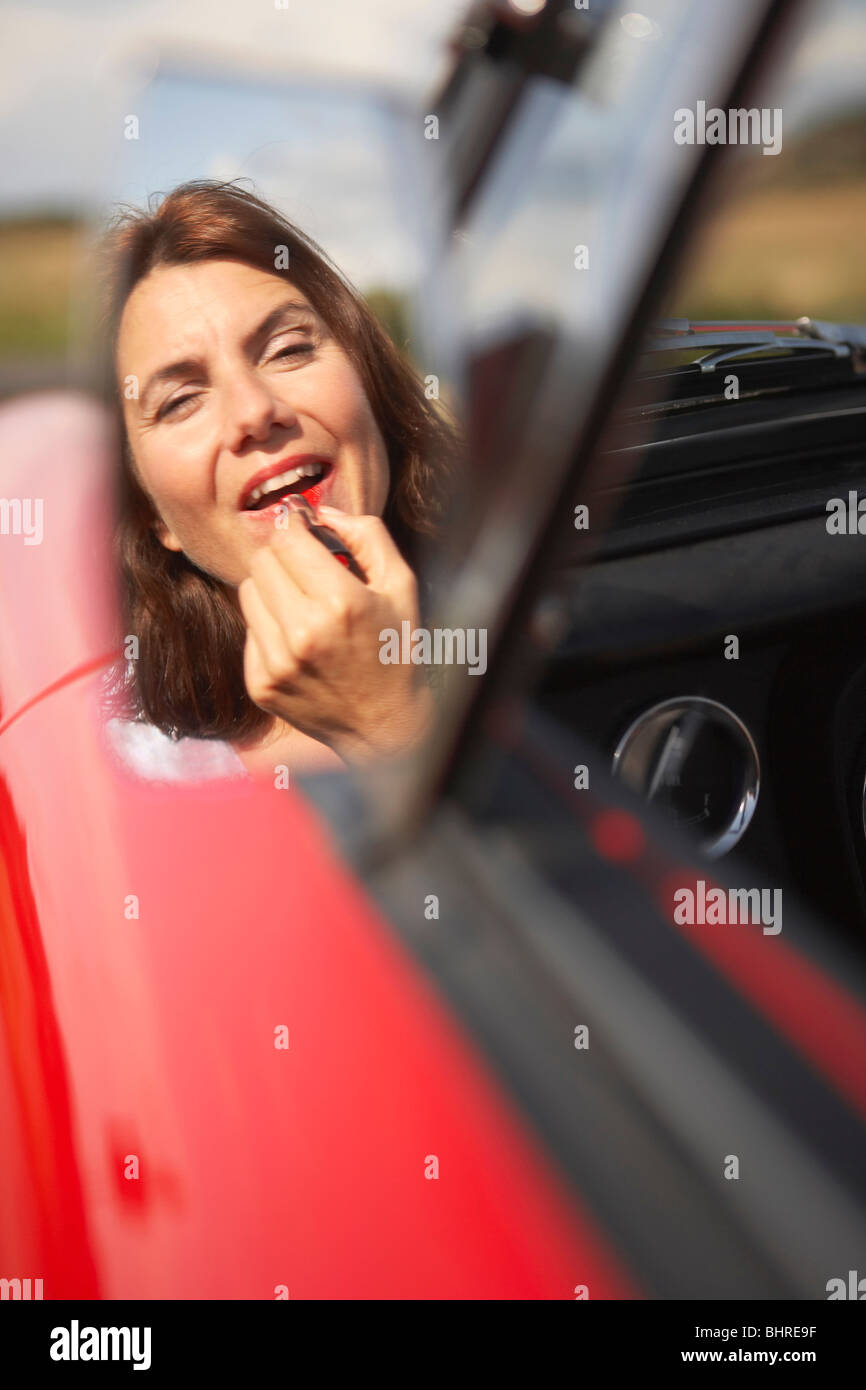 Woman applying lipstick in cars mirror Stock Photo - Alamy