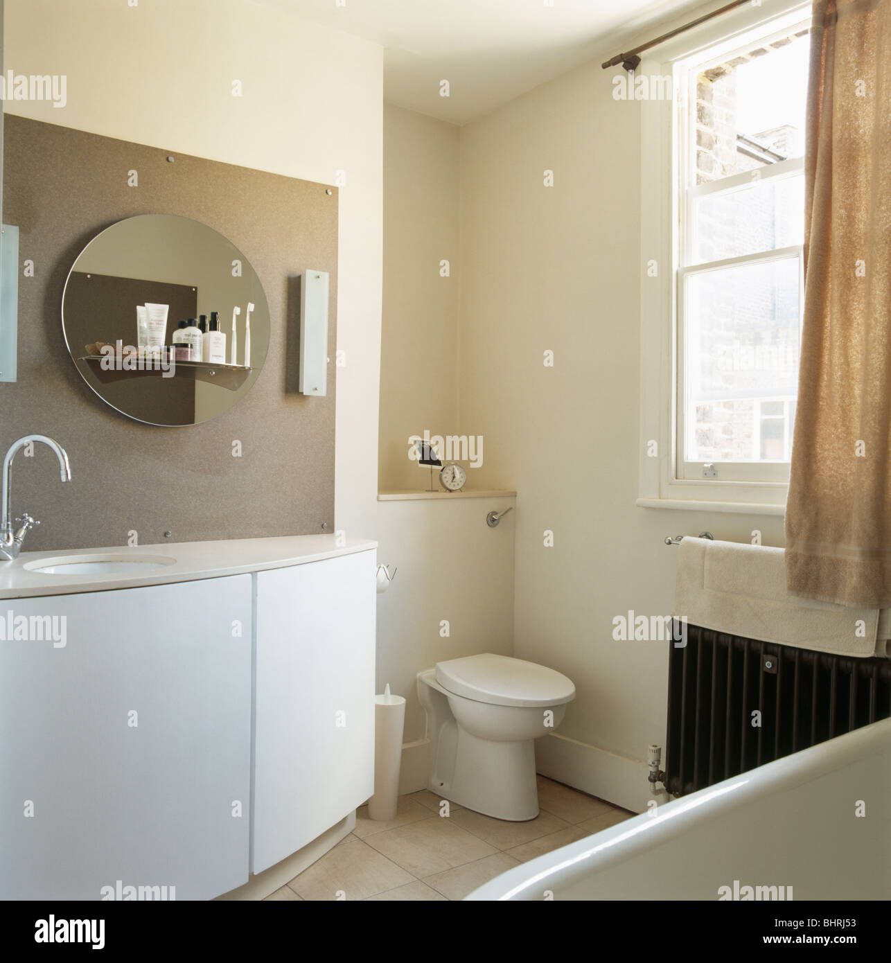 Circular mirror on concrete panel above vanity unit in modern bathroom ...