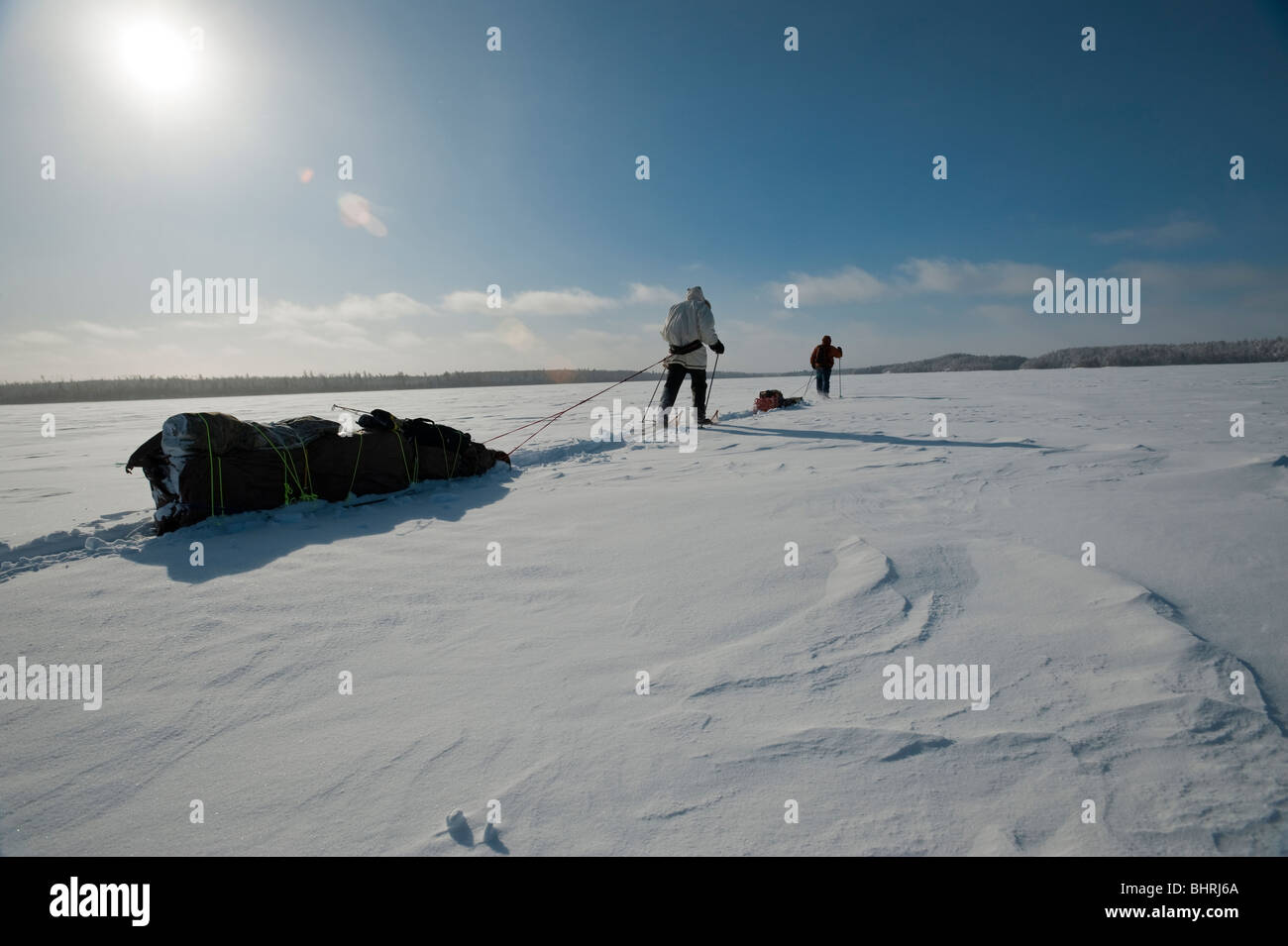 TWO MEN PULL PULKS ACROSS SAGANAGA LAKE QUETICO PROVINCIAL PARK CANADA ...