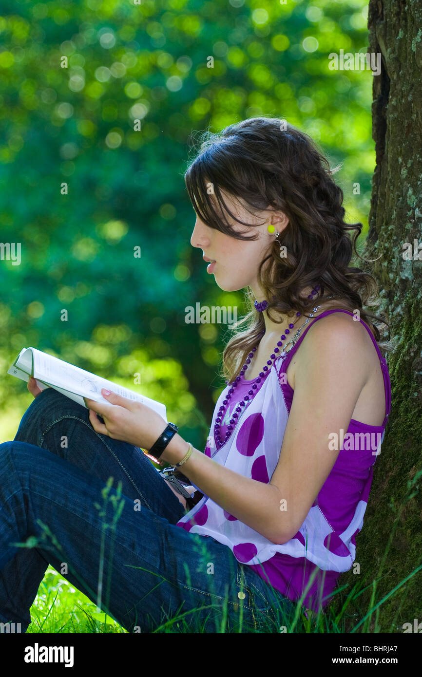Blond girl reading a book in a park Stock Photo - Alamy