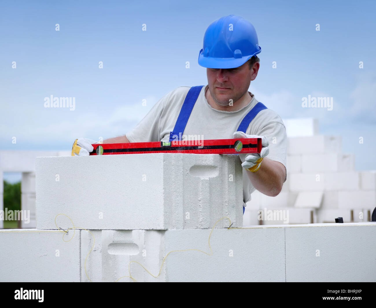 Mason checking horizontal level of house wall layer being made from ...
