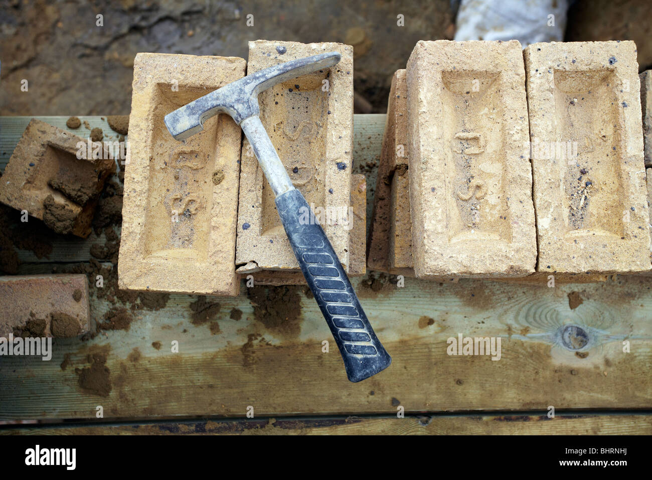 Bricklayers hammer on bricks ready to be laid in a wall on a building ...