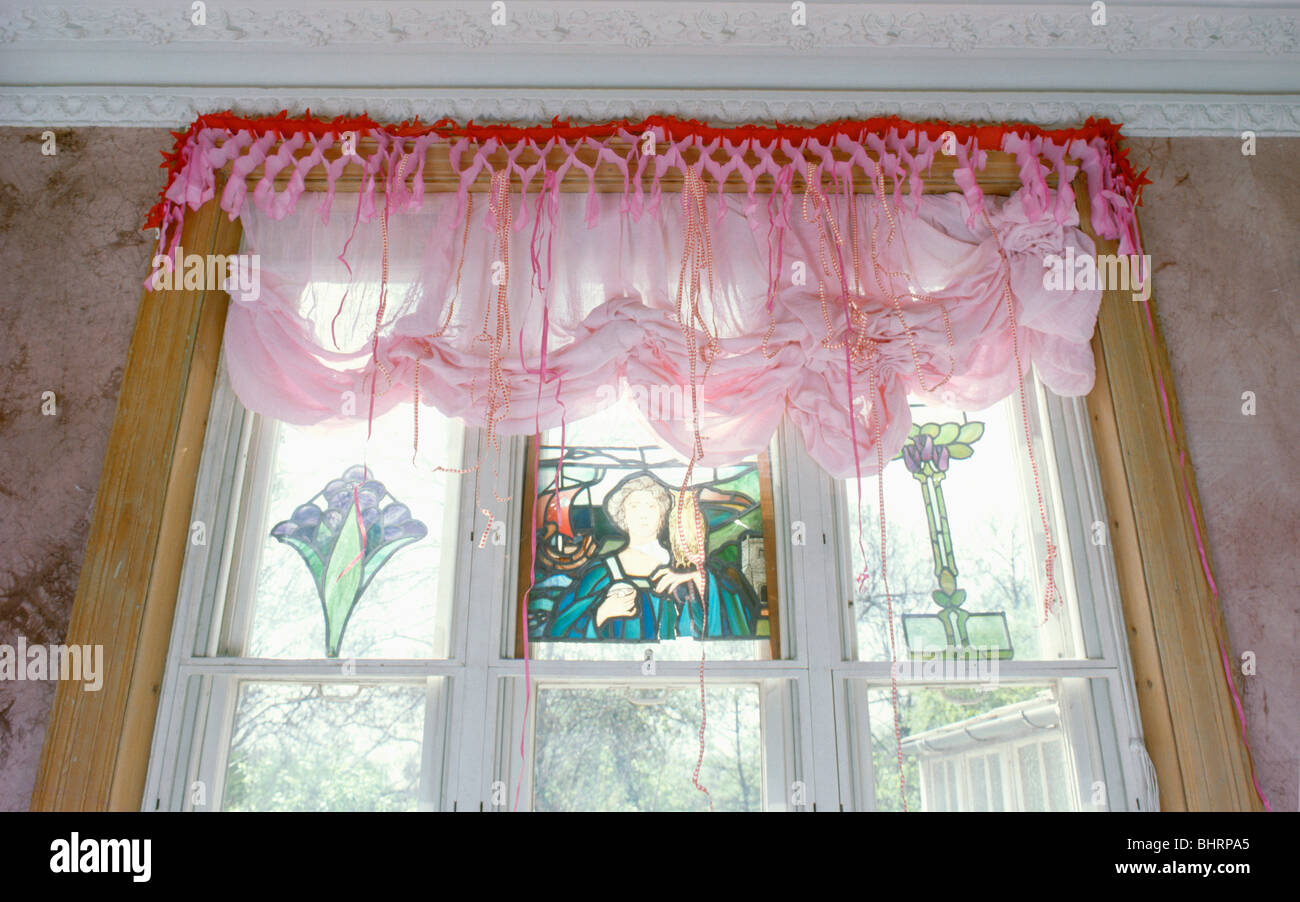 Close-up of pink voile festoon blind on stained glass window Stock ...