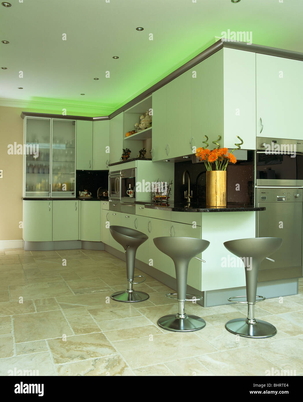 Green halogen lighting above fitted white cupboards in modern kitchen ...