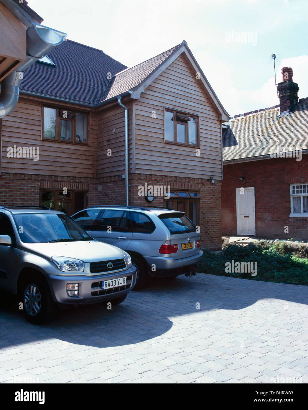 Cars on paved drive in front of timbered new-build house Stock Photo ...