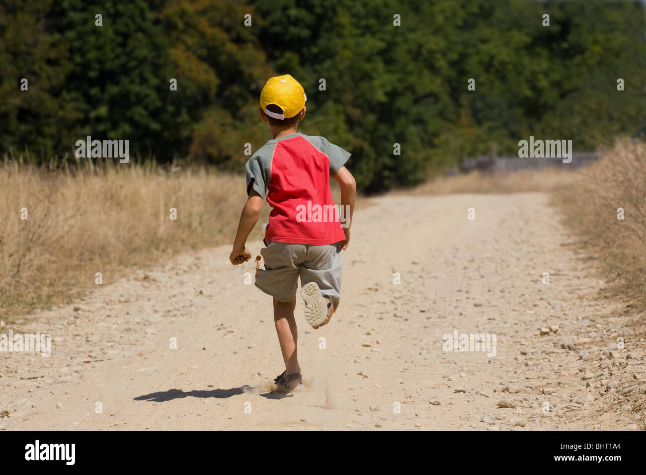 Seven year old kid running on a dusty road in the countryside Stock ...