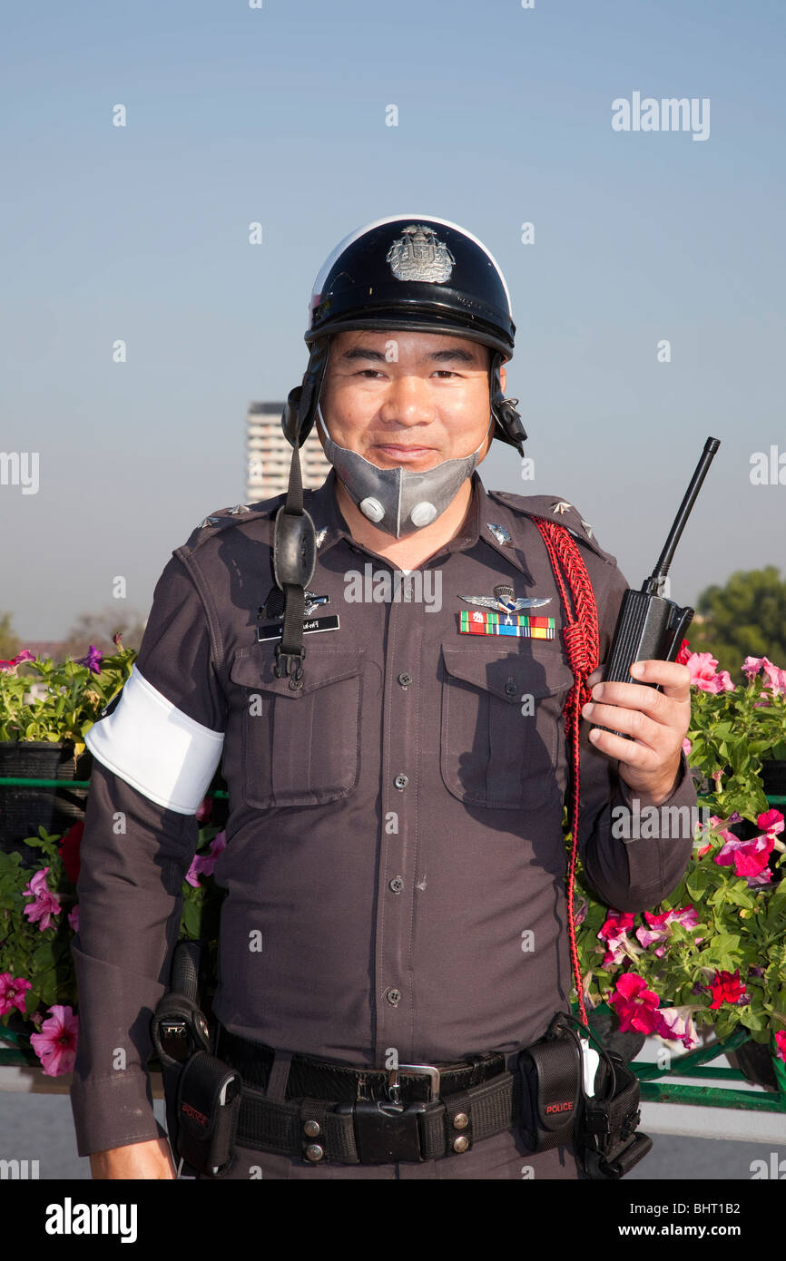 Uniformed Thai Policeman holding police radio, wearing pollution mask ...