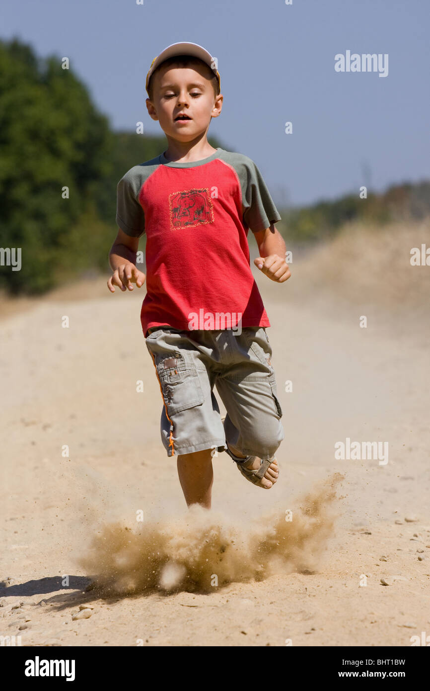 Seven year old kid running on a dusty road in the countryside Stock ...