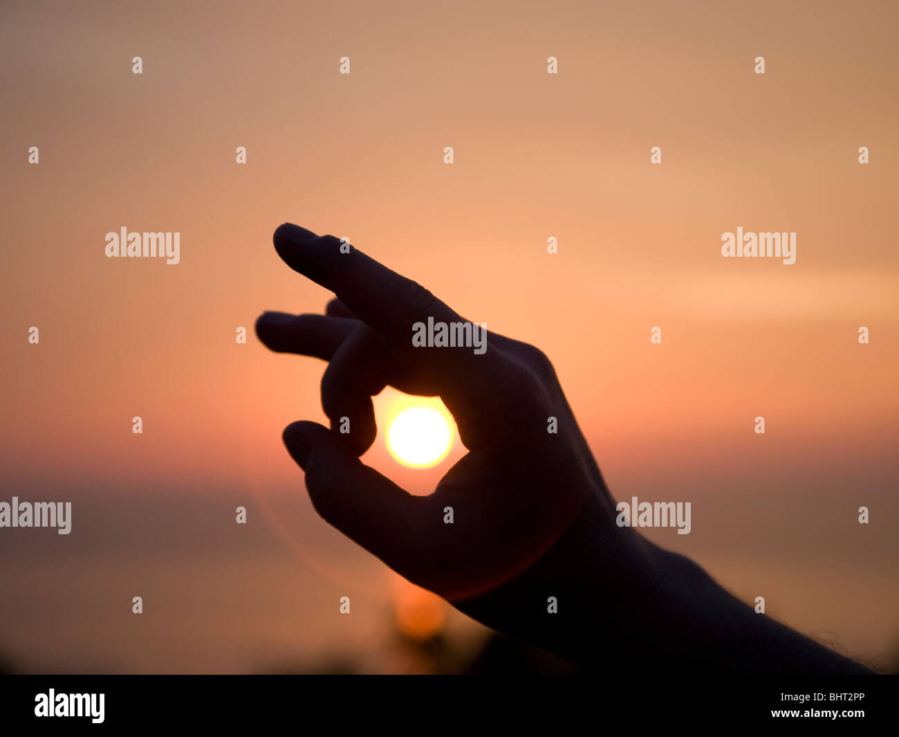 Hand Capturing the sun at sunset - Phuket Stock Photo - Alamy