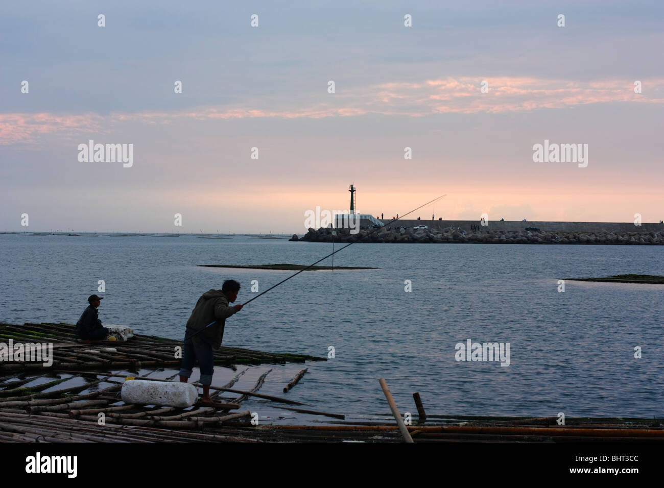 Locals fish off wrecked oyster racks in AnPing Harbor at sunset. Tainan ...