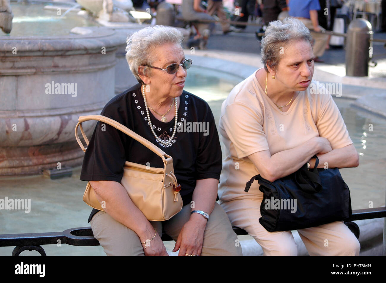 elderly ladies sitting on fountain railing people watching in Piazza ...