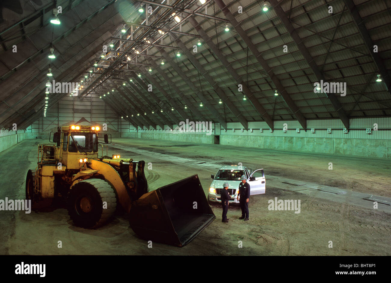 two workers standing around a coal storage site with loader Stock Photo ...
