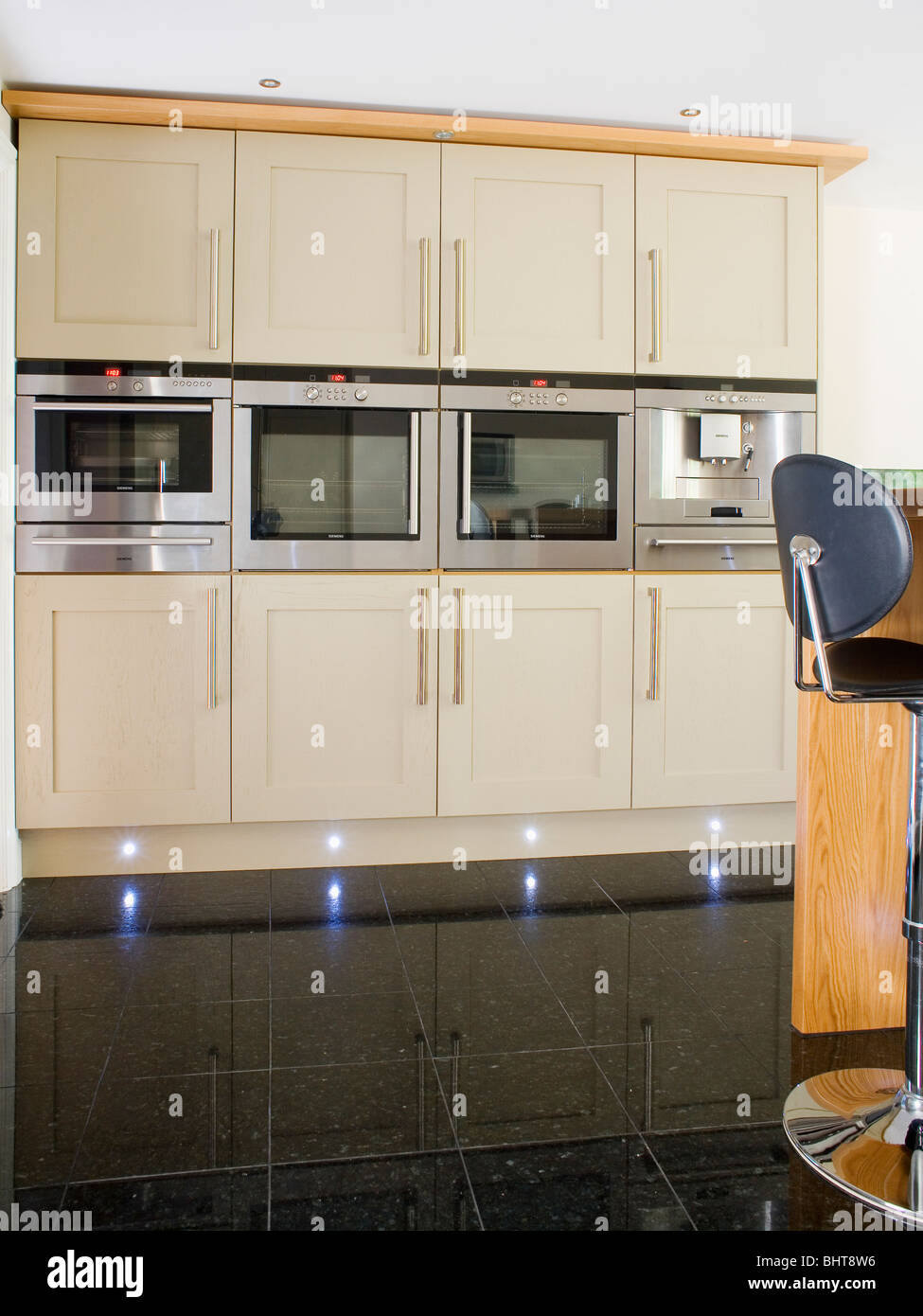 Modern kitchen with row of eye-level double ovens in fitted cream units ...