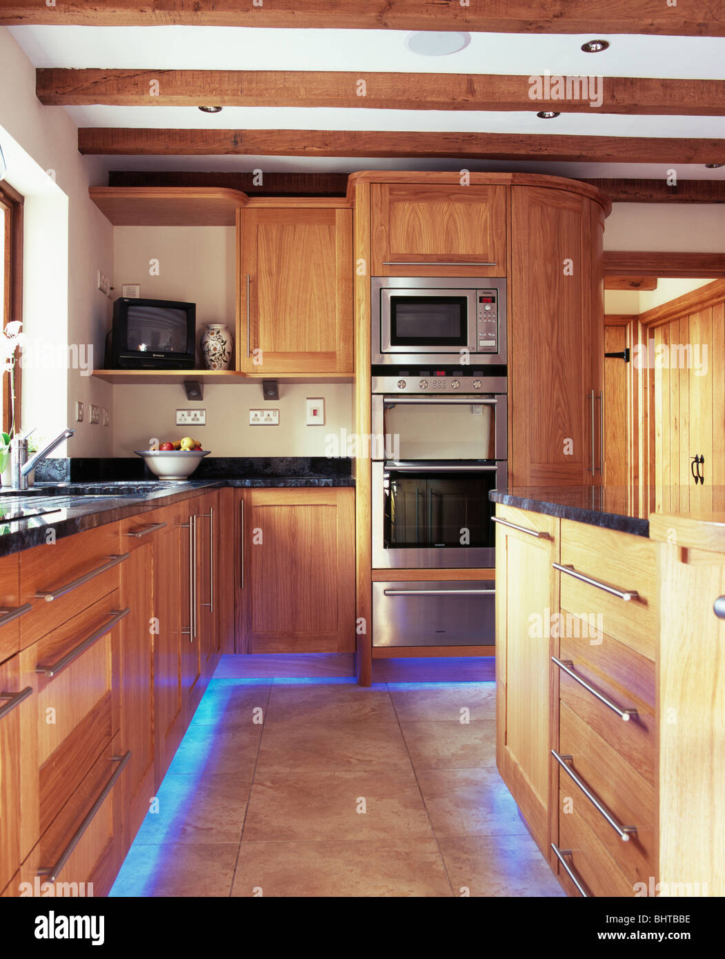 Blue halogen lighting below fitted units in modern country kitchen with ...