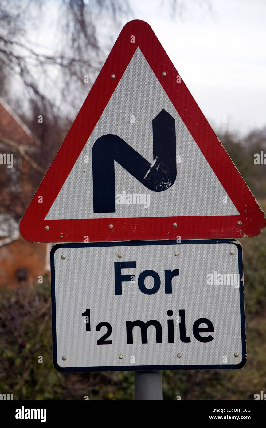 Red triangular sign for corners in road for half mile ahead Stock Photo ...