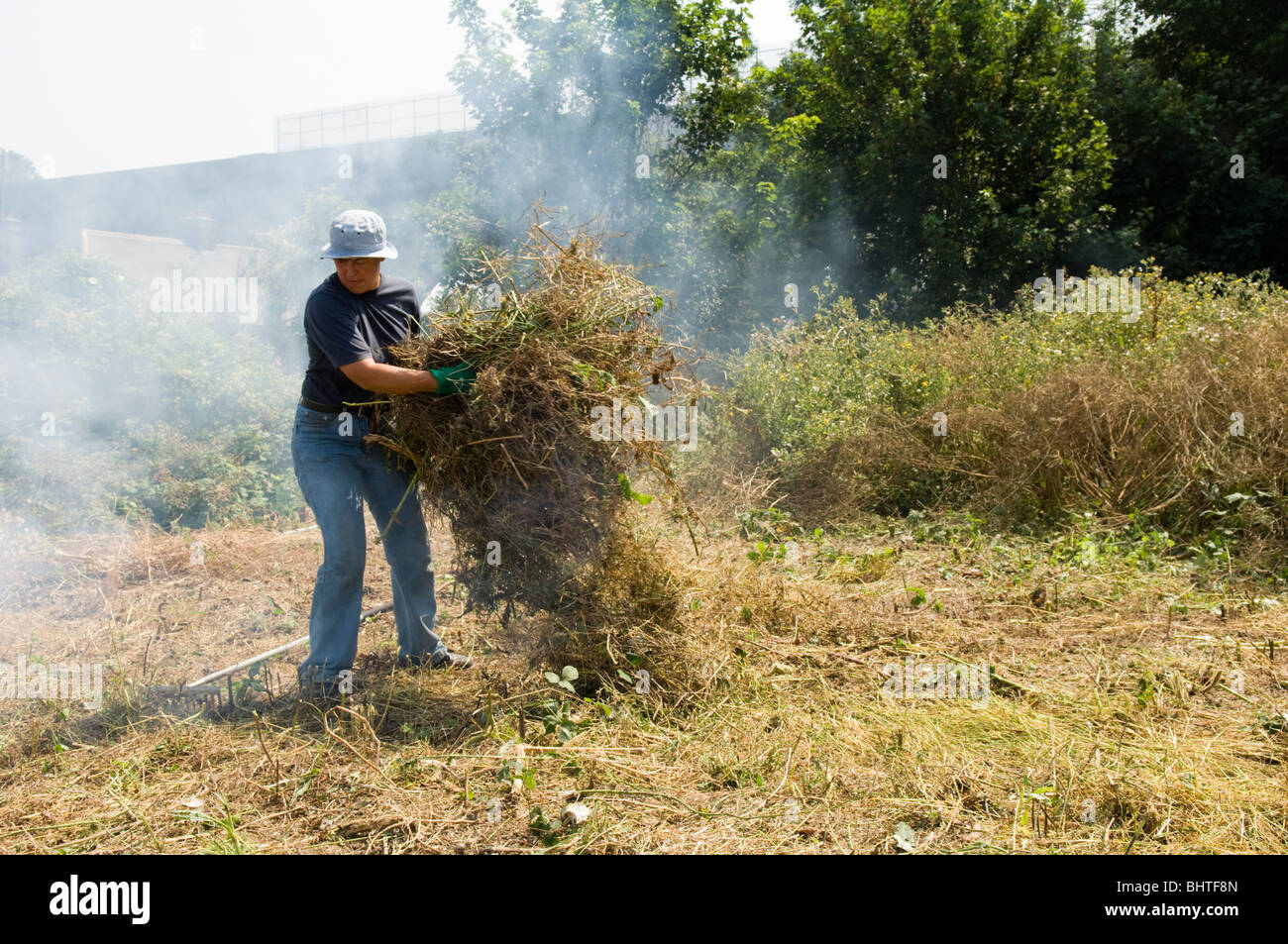 Woman clearing overgrown allotment plot and burning the cut weeds Stock ...