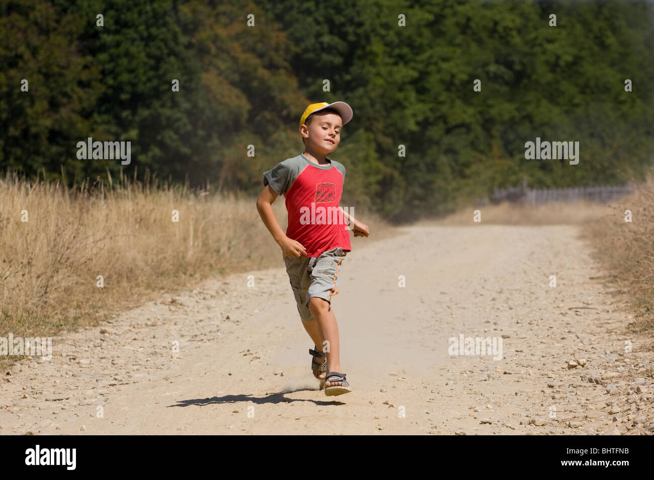 Seven year old kid running on a dusty road in the countryside Stock ...