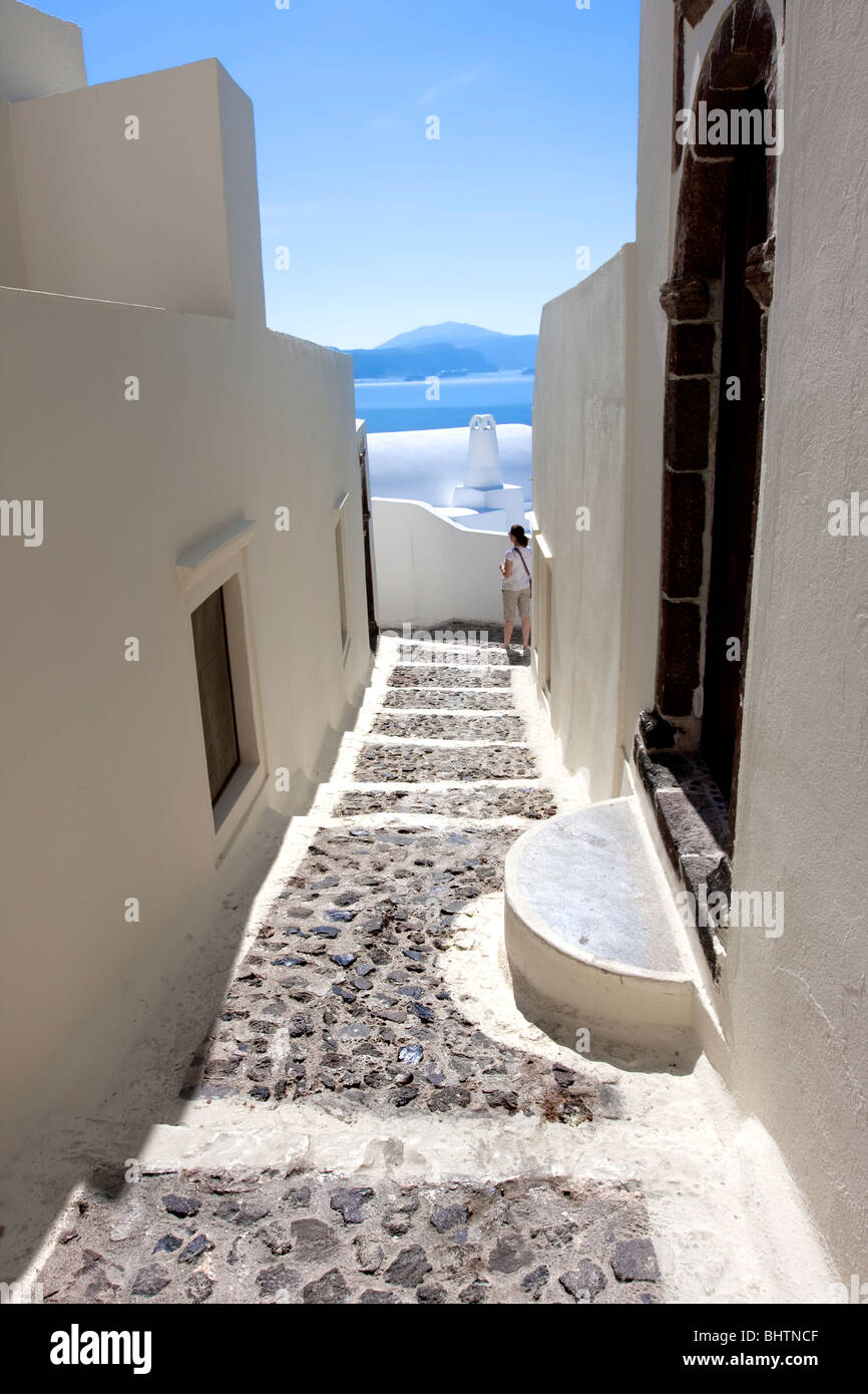 A narrow path between white washed buildings in Santorini Greece, with ...
