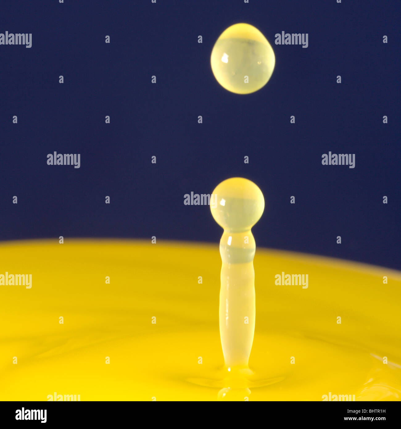 Yellow dripping water against a blue background Stock Photo - Alamy