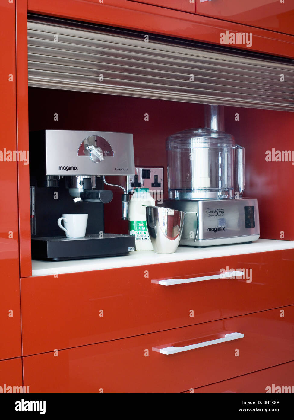 Close-up of expresso coffee machine and food processor on shelf in red ...