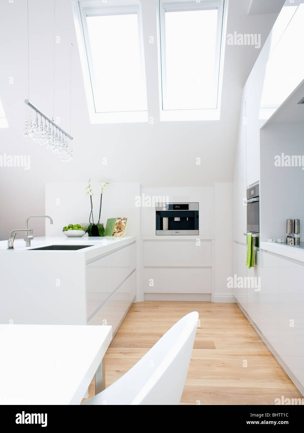 Modern white kitchen with wooden flooring in loft conversion apartment ...