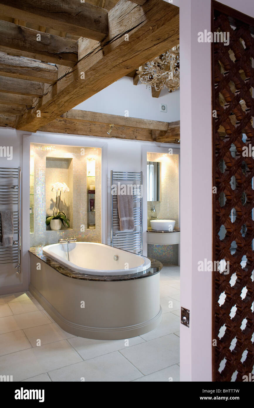 Bath extending into modern white bathroom with beamed ceiling and ...