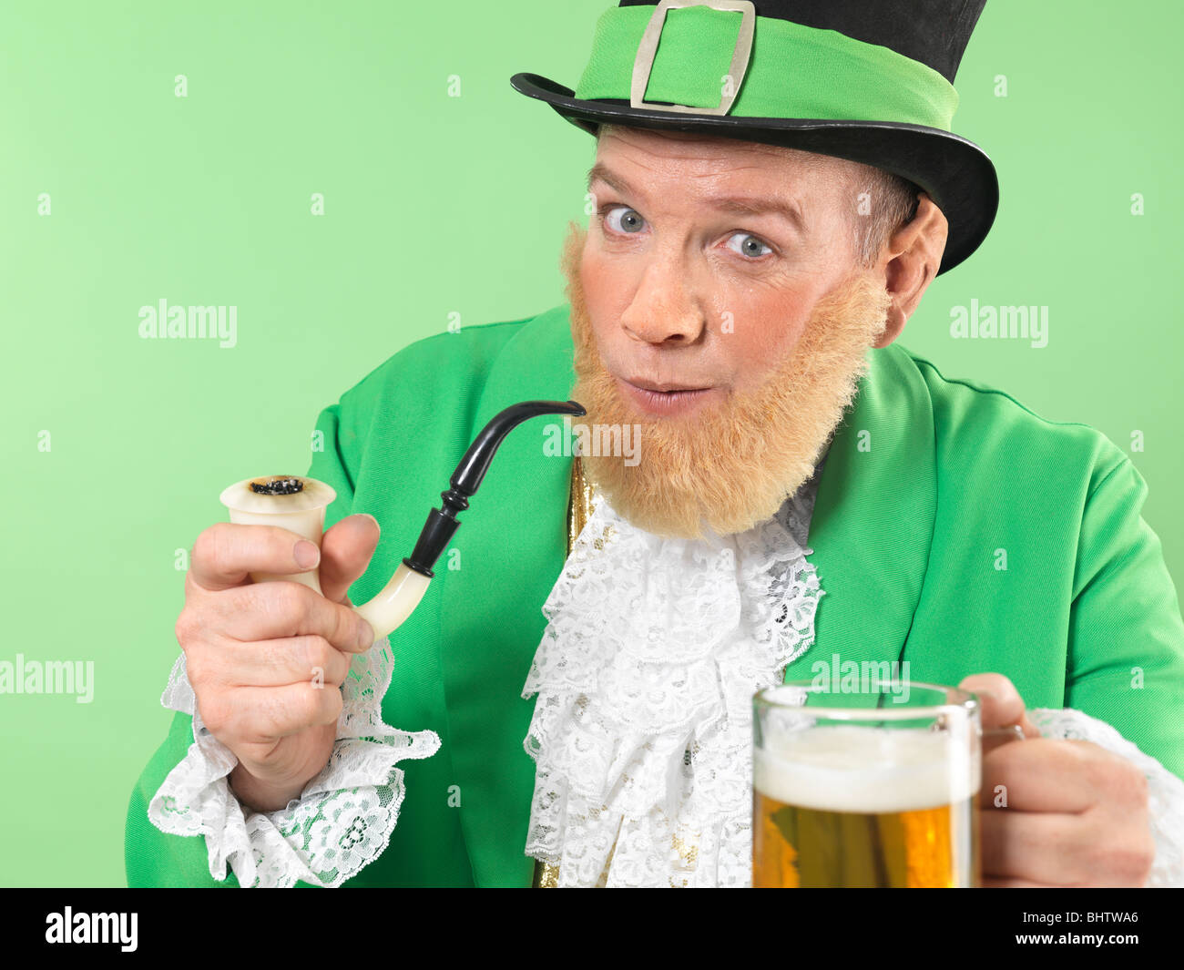 Cheerful Leprechaun in bright green clothes holding a smoking pipe and ...