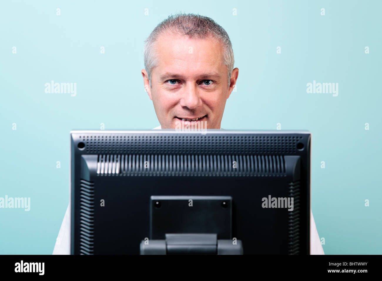 Mature man working at a computer looking over the screen Stock Photo ...