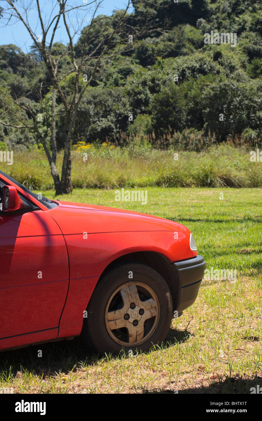 Red motor car parked at entrance to nature trail through the bush ...