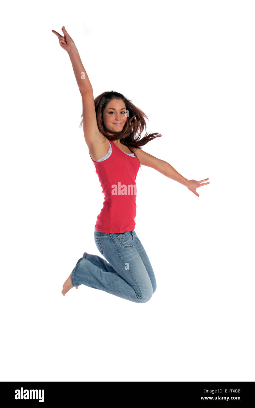 An attractive young woman jumping in front of a plain white background ...