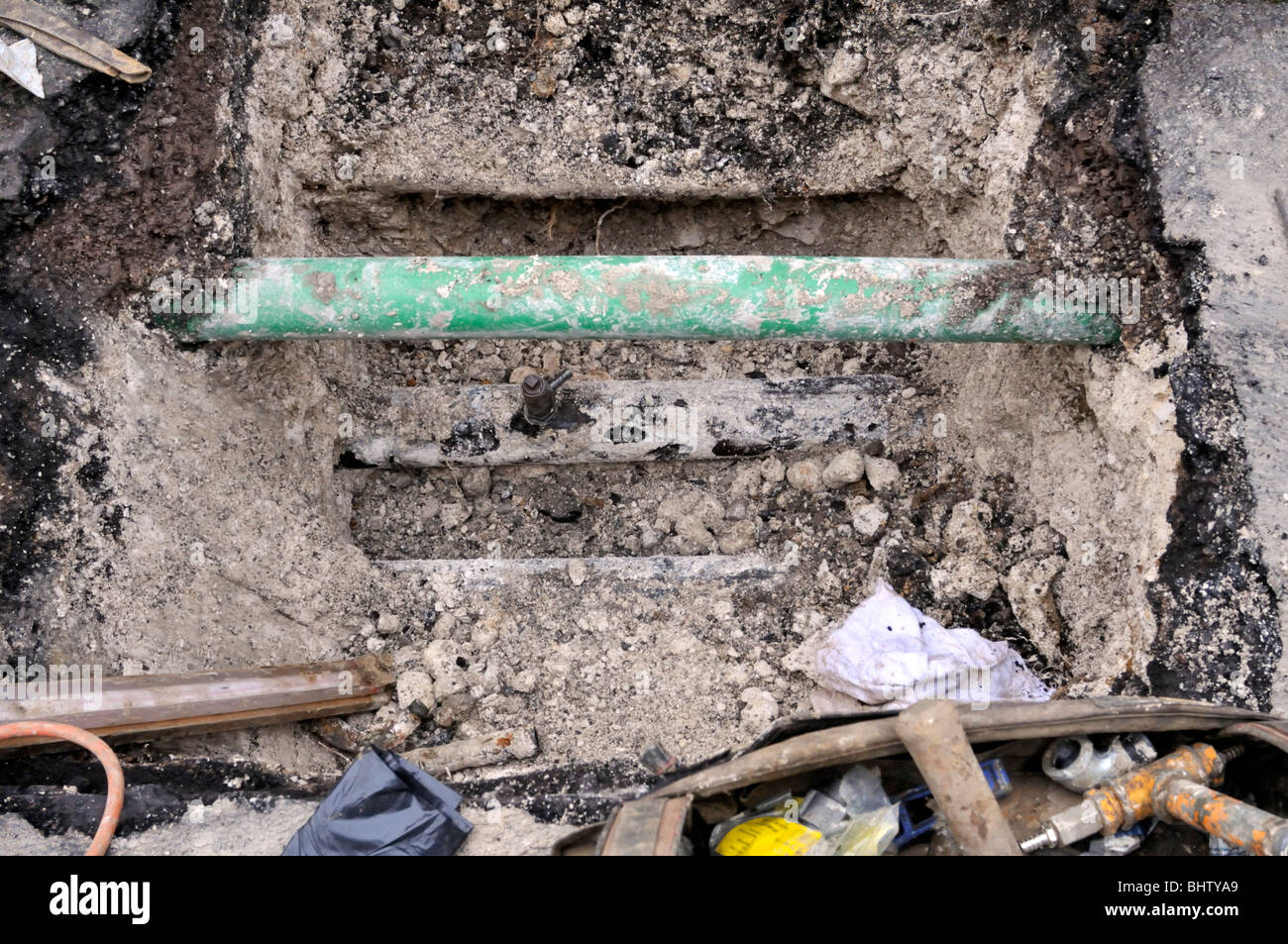 Old metal gas pipe visible below the green fiber optic pipe Stock Photo ...
