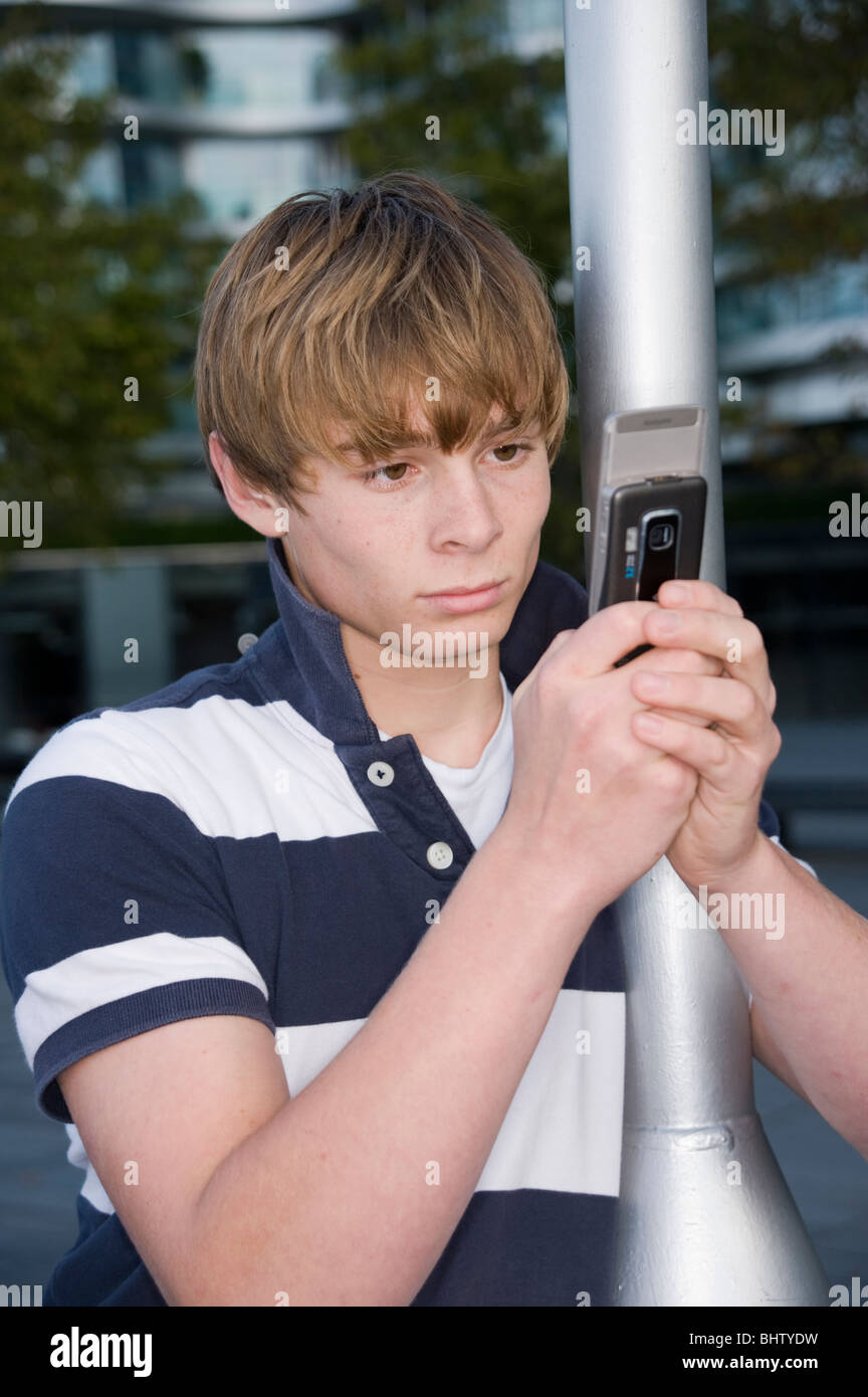 teenage boy looking at has mobile phone reading messages or looking at ...