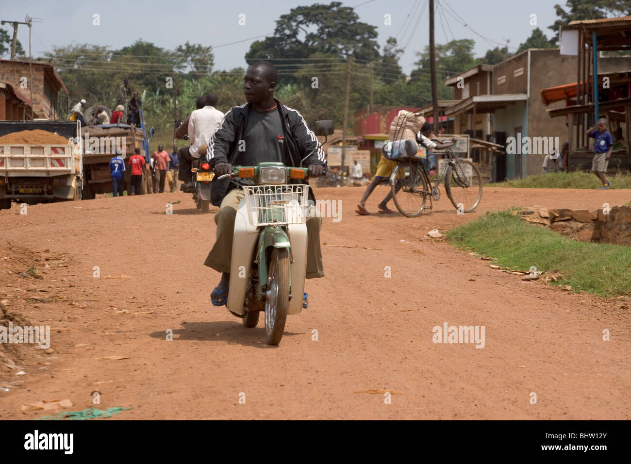 Man traveling on a moped through a rural village in Uganda Stock Photo ...
