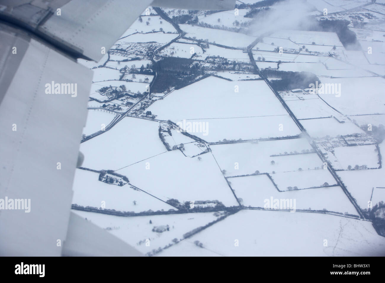 Looking out of an aircraft window flying over snow covered fields in ...