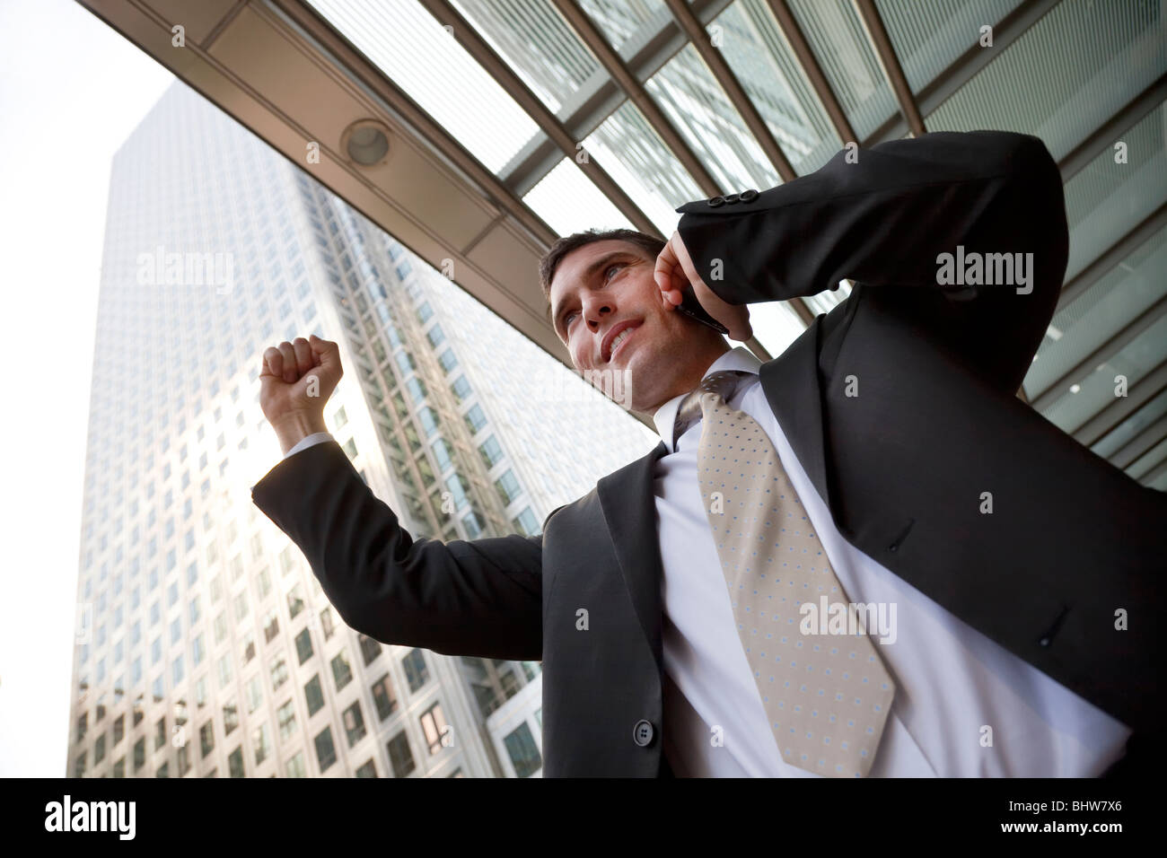A happy businessman talking on his cell phone with his arm out ...