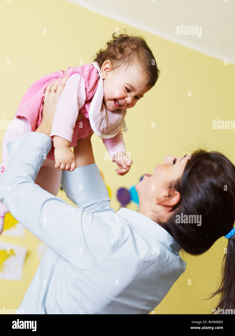 mom lifting her daughter up and smiling. Vertical shape Stock Photo - Alamy