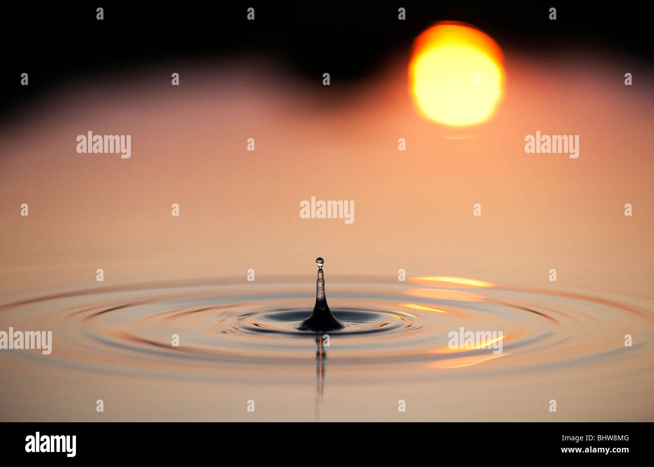 Water drops and ripples in a pool with reflected sunrise background ...