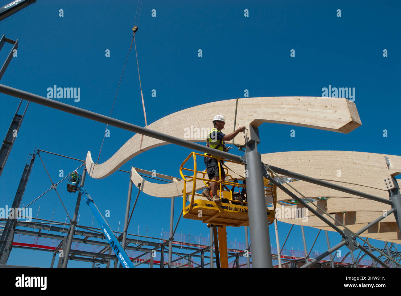 High level Construction workers building laminated wood wave roof on ...