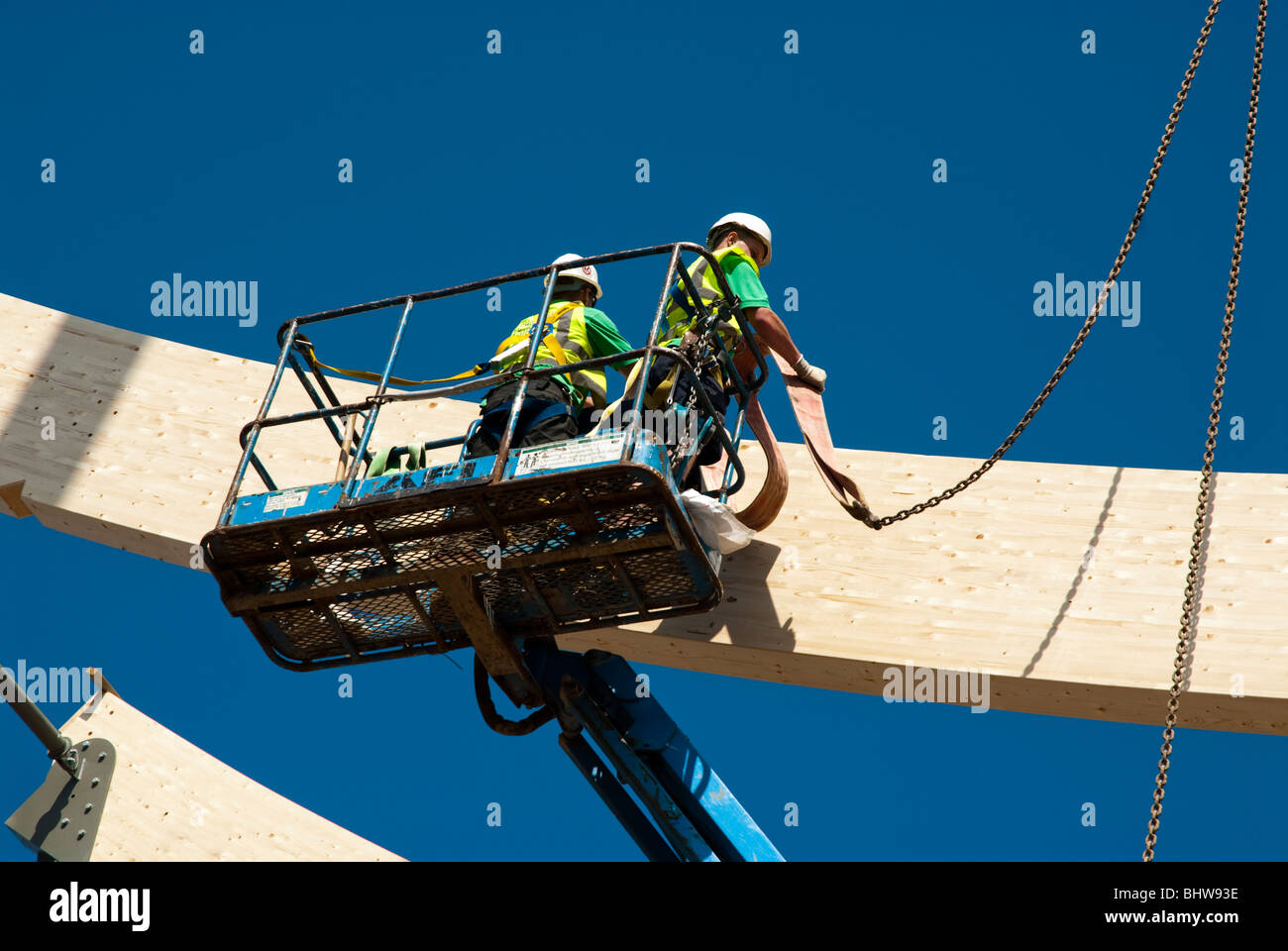 High level Construction workers building laminated wood wave roof on ...