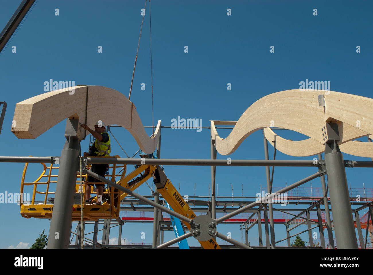 High level Construction workers building laminated wood wave roof on ...