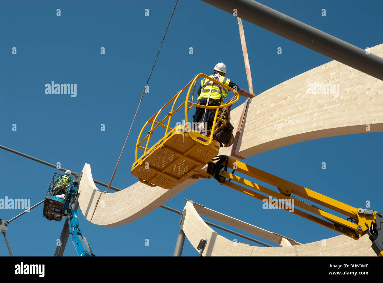 High level Construction workers building laminated wood wave roof on ...