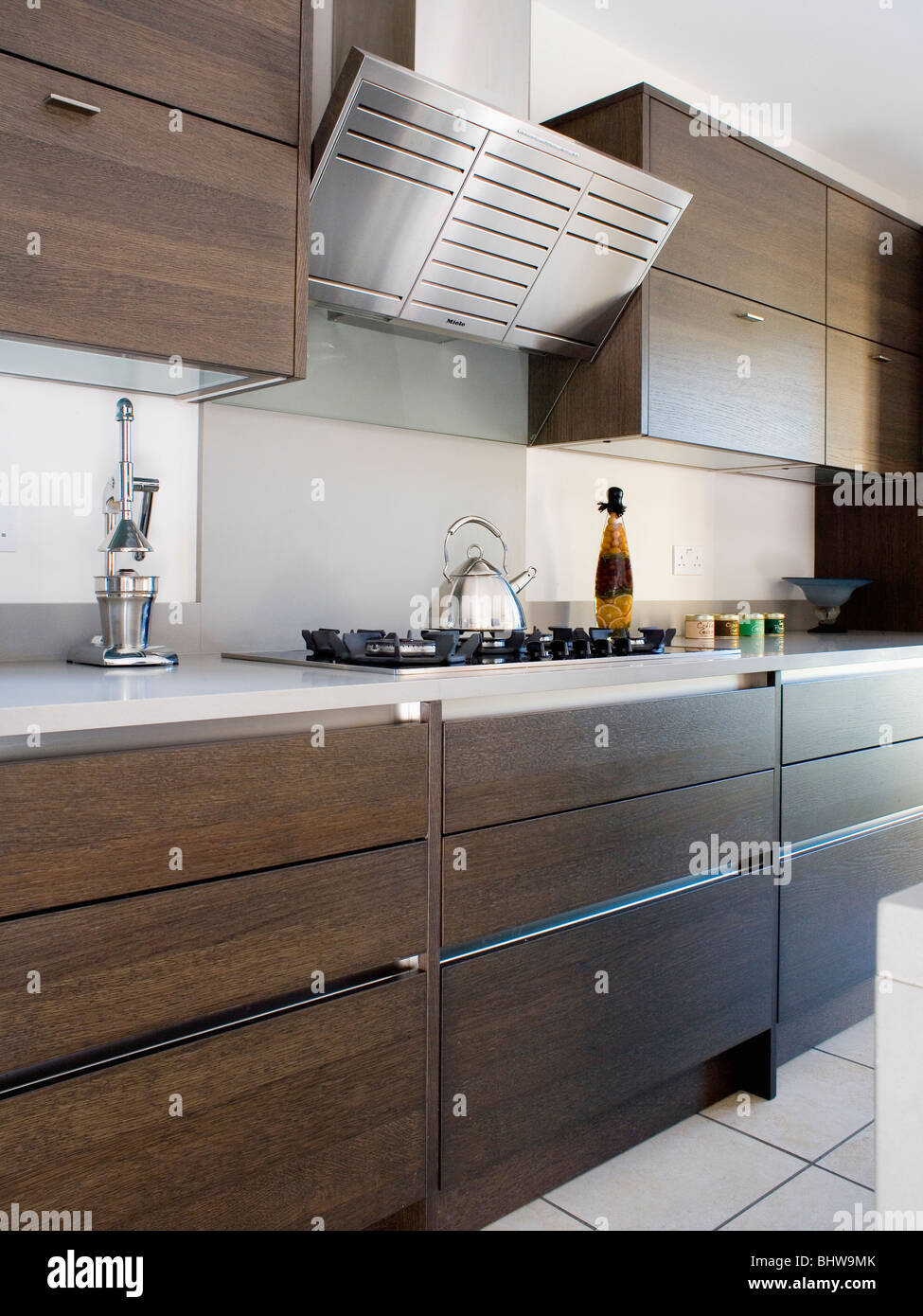 Retractable stainless-steel extractor above chrome kettle on hob in ...