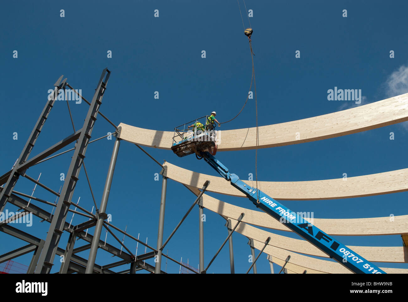 High level Construction workers building laminated wood wave roof on ...