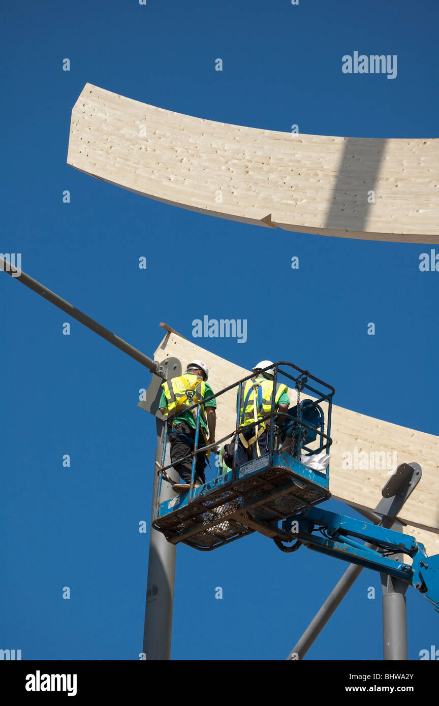 High level Construction workers building laminated wood wave roof on ...