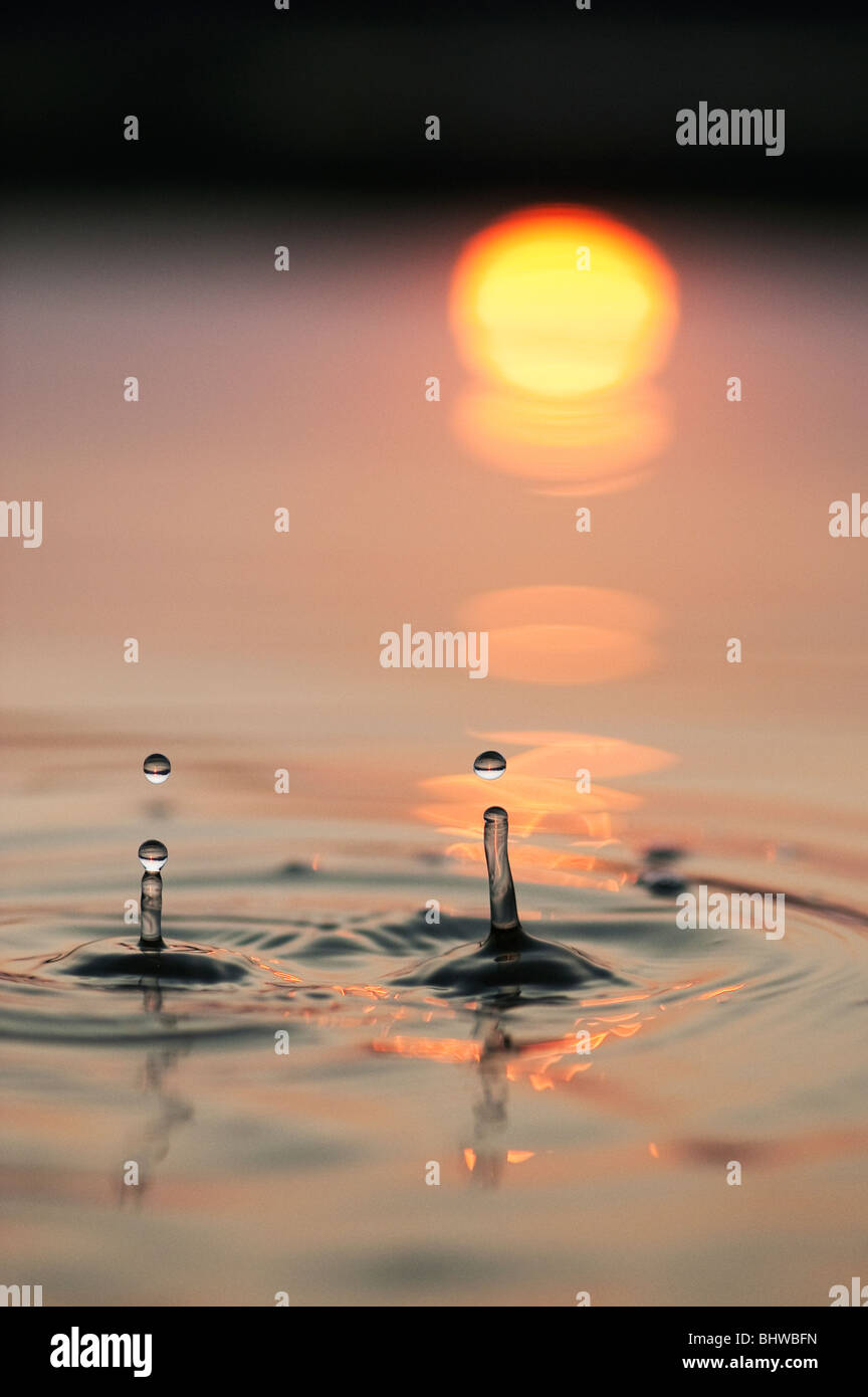 Water drops and ripples in a pool with reflected sunrise background ...