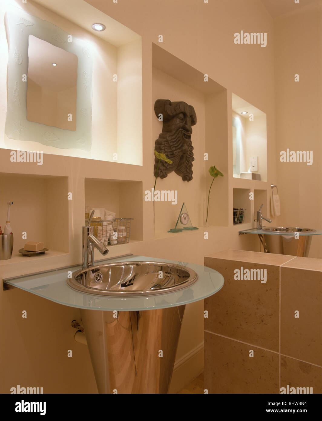 Close-up of mirror in lighted alcove above modern stainless steel ...